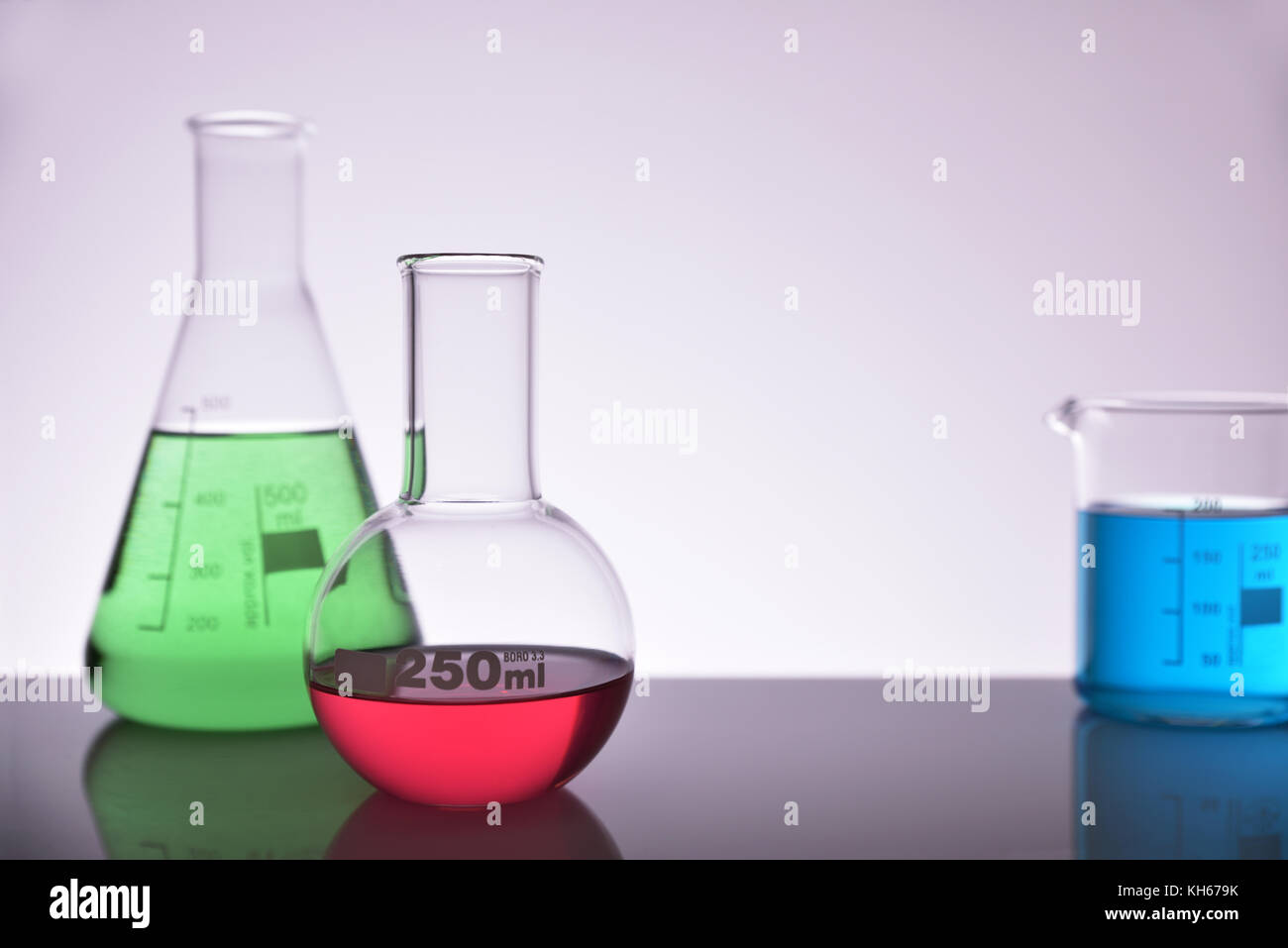 Laboratory glass chemical containers on glass table isolated gray ...