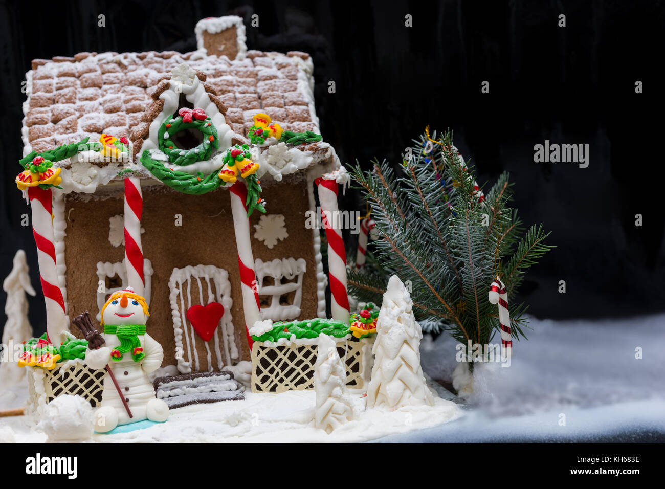 Big snow-covered homemade gingerbread house, a sprig of Christmas tree ...