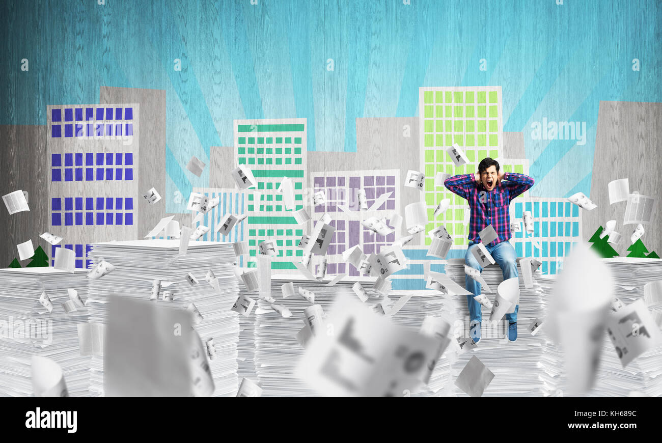 Young man sitting on pile of paper documents Stock Photo - Alamy