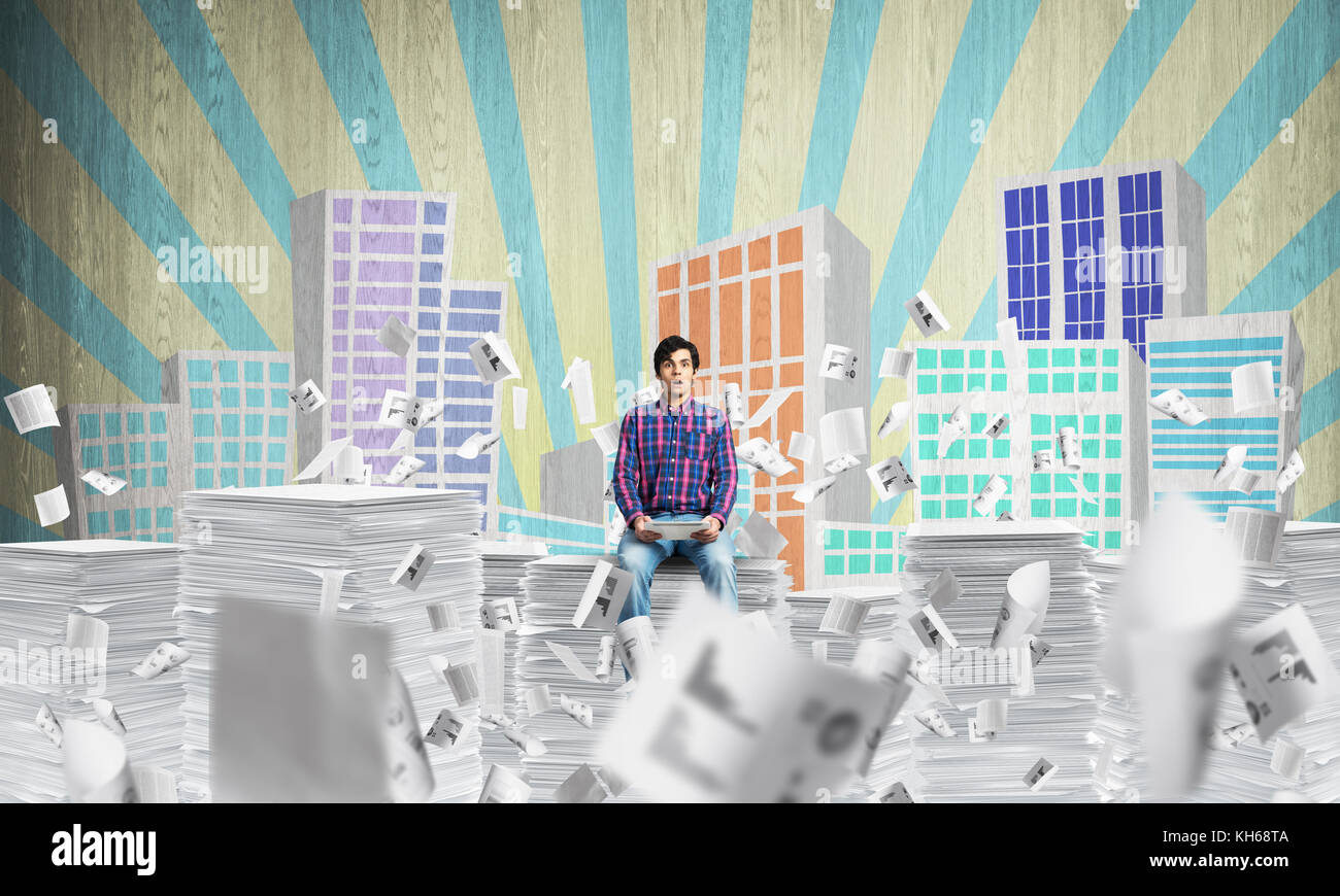 Young man sitting on pile of paper documents Stock Photo - Alamy