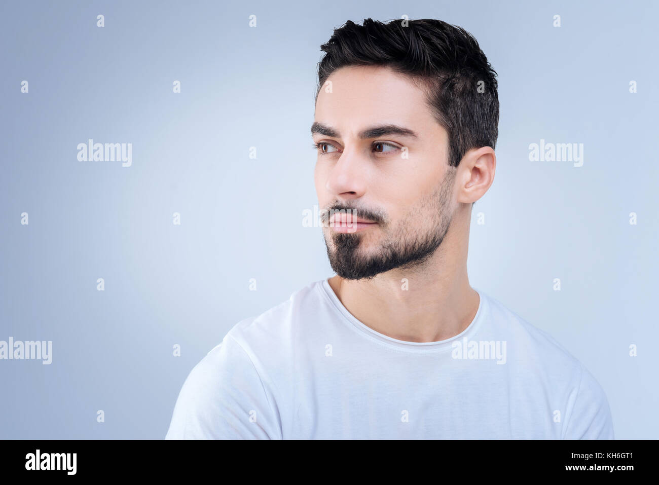 Elegant pleasant man looking to the left side and slightly smiling ...