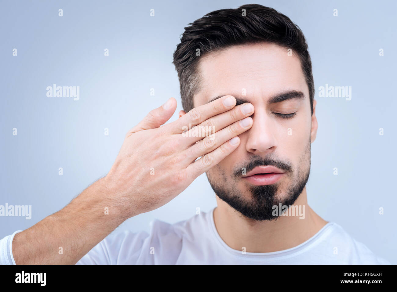 Calm man standing with his eyes closed while curing them Stock Photo ...