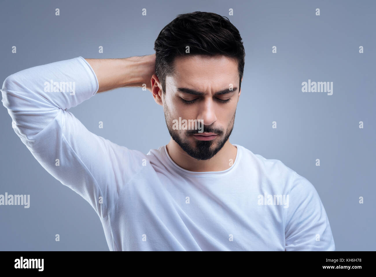 Calm young man scratching his head while standing and thinking Stock ...