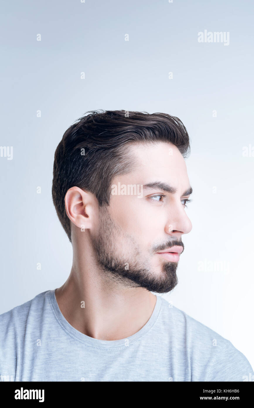 Calm handsome man turning left and thinking while sitting at home Stock ...
