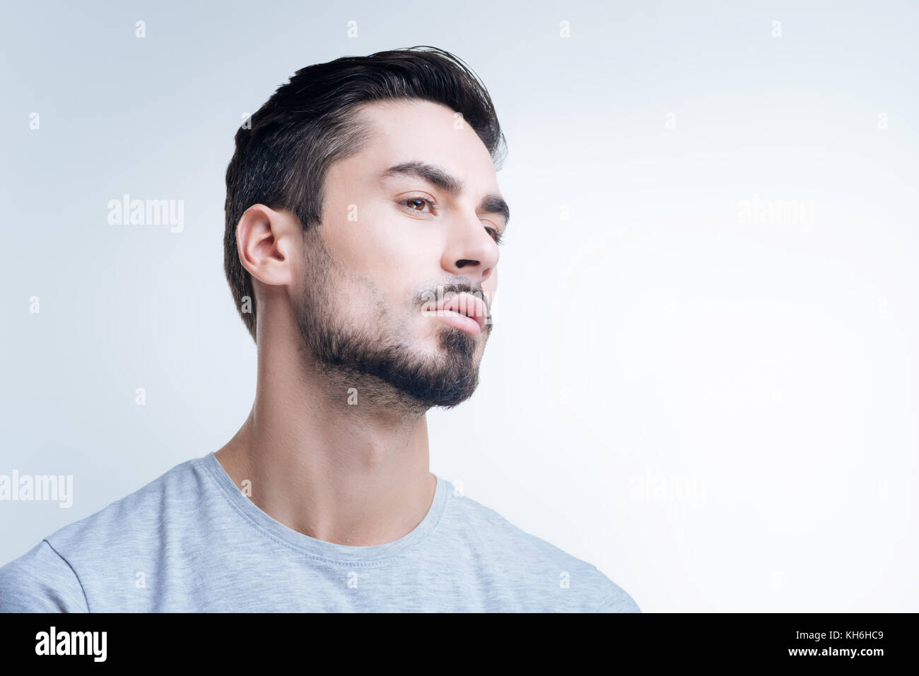 Unpleasant young man looking not very friendly while standing alone ...