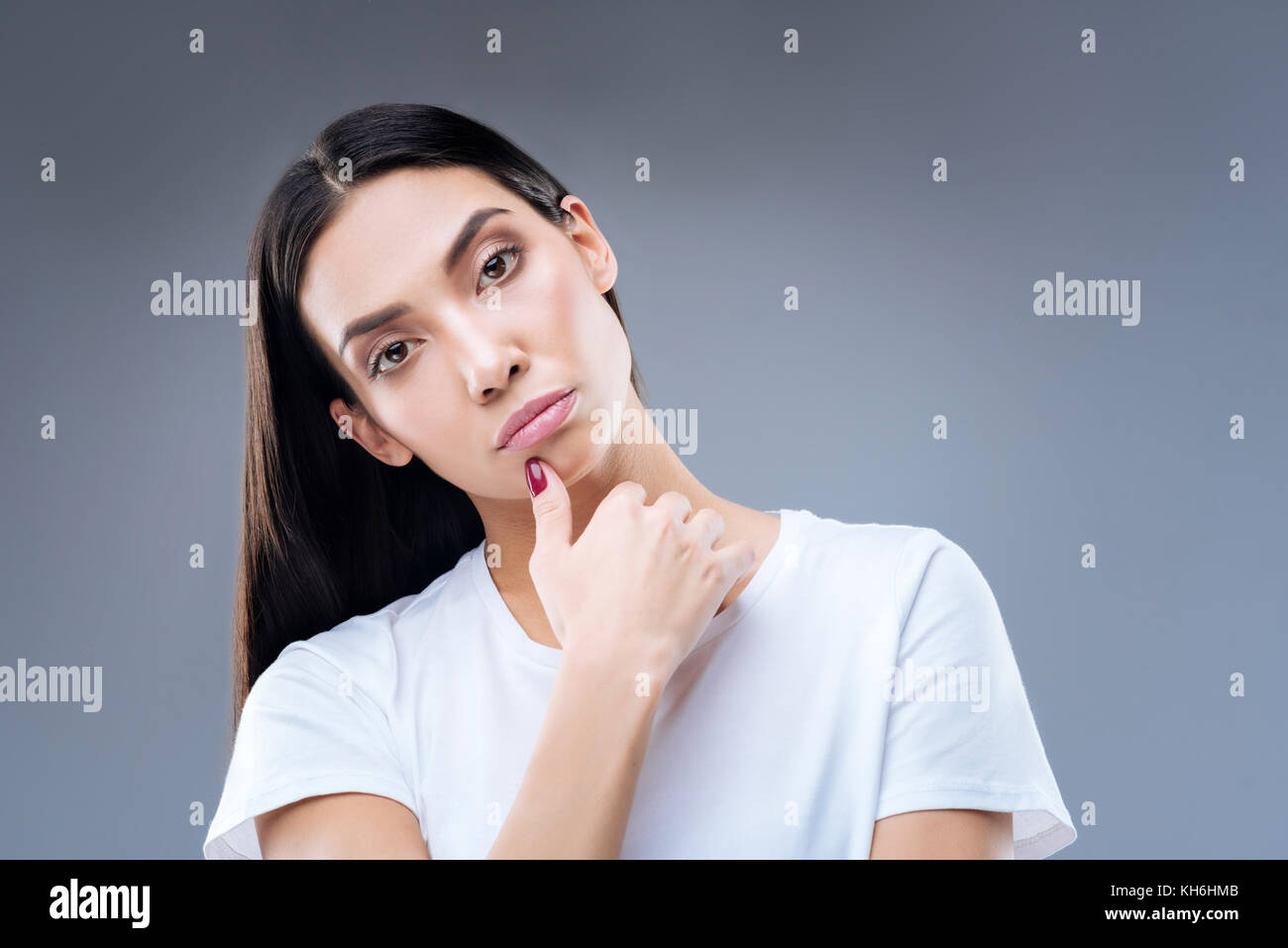 Smart woman leaning her head to the right while looking at the picture ...