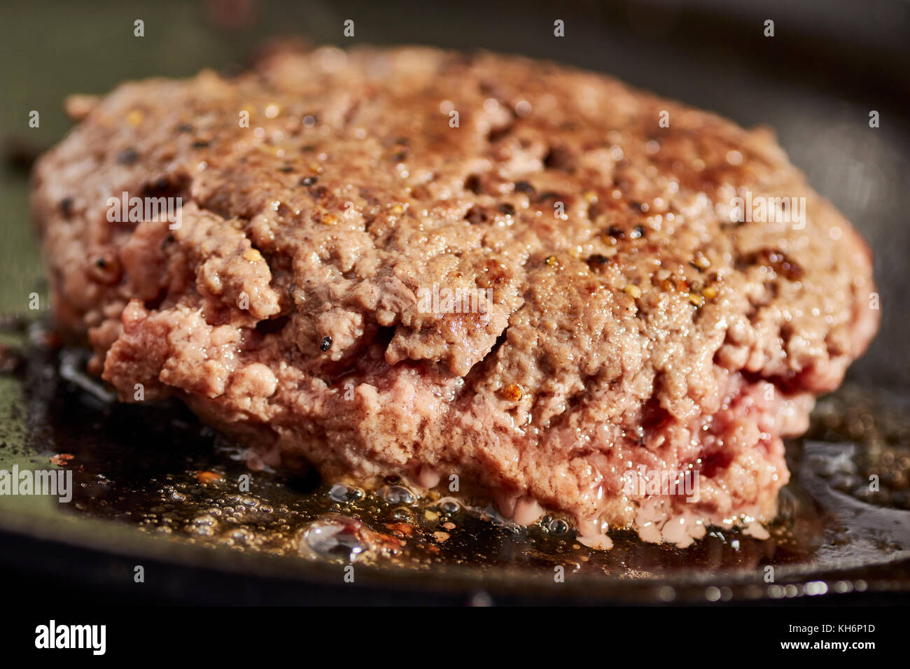 A hamburger patty frying on a cast iron grill Stock Photo - Alamy