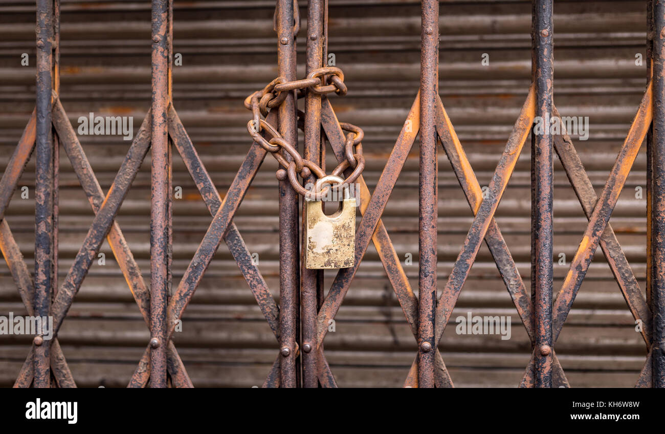 Closed collapsible gate with old rusty chain and lock in selective ...