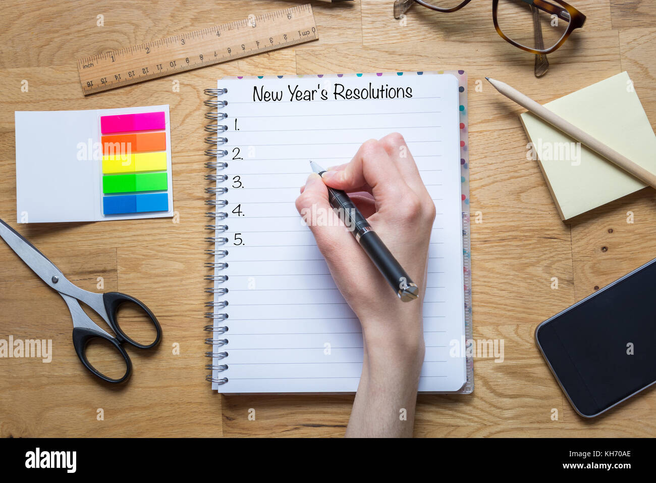 Writing on notepad with new year's resolutions at the top and list ...