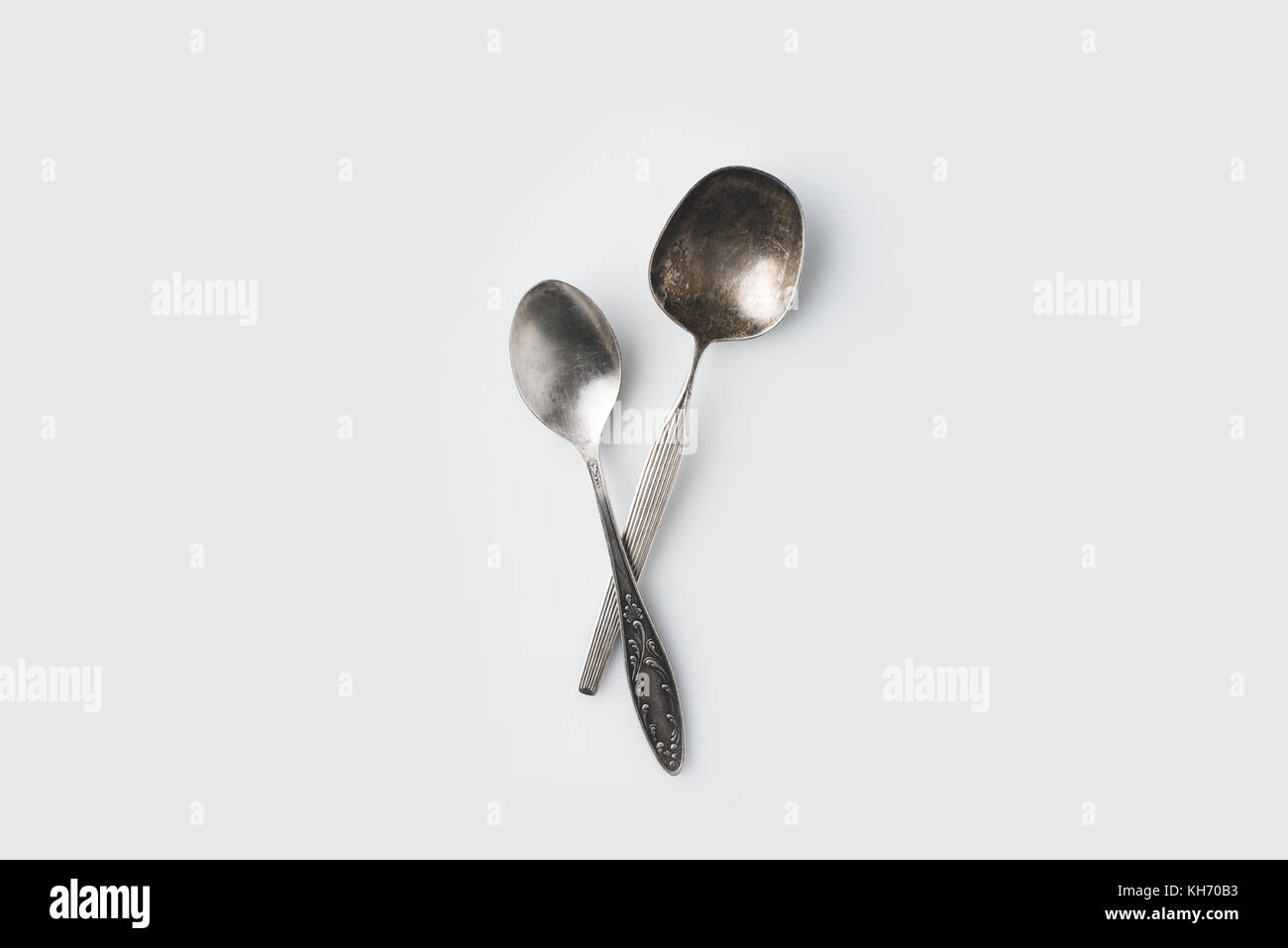 crossed spoons on white table Stock Photo - Alamy