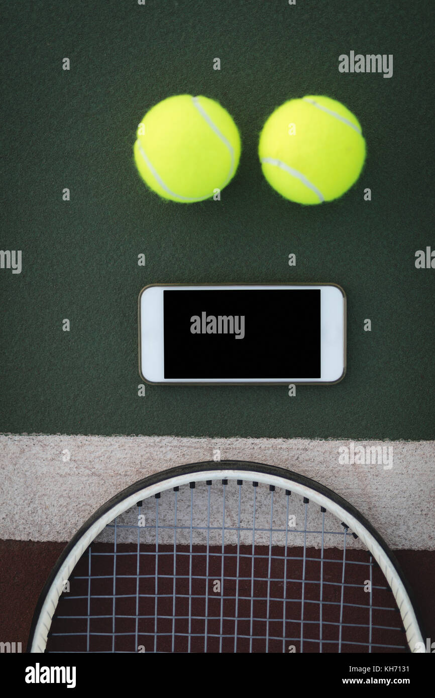 Overhead of mobile phone, racket and tennis ball in ground Stock Photo ...