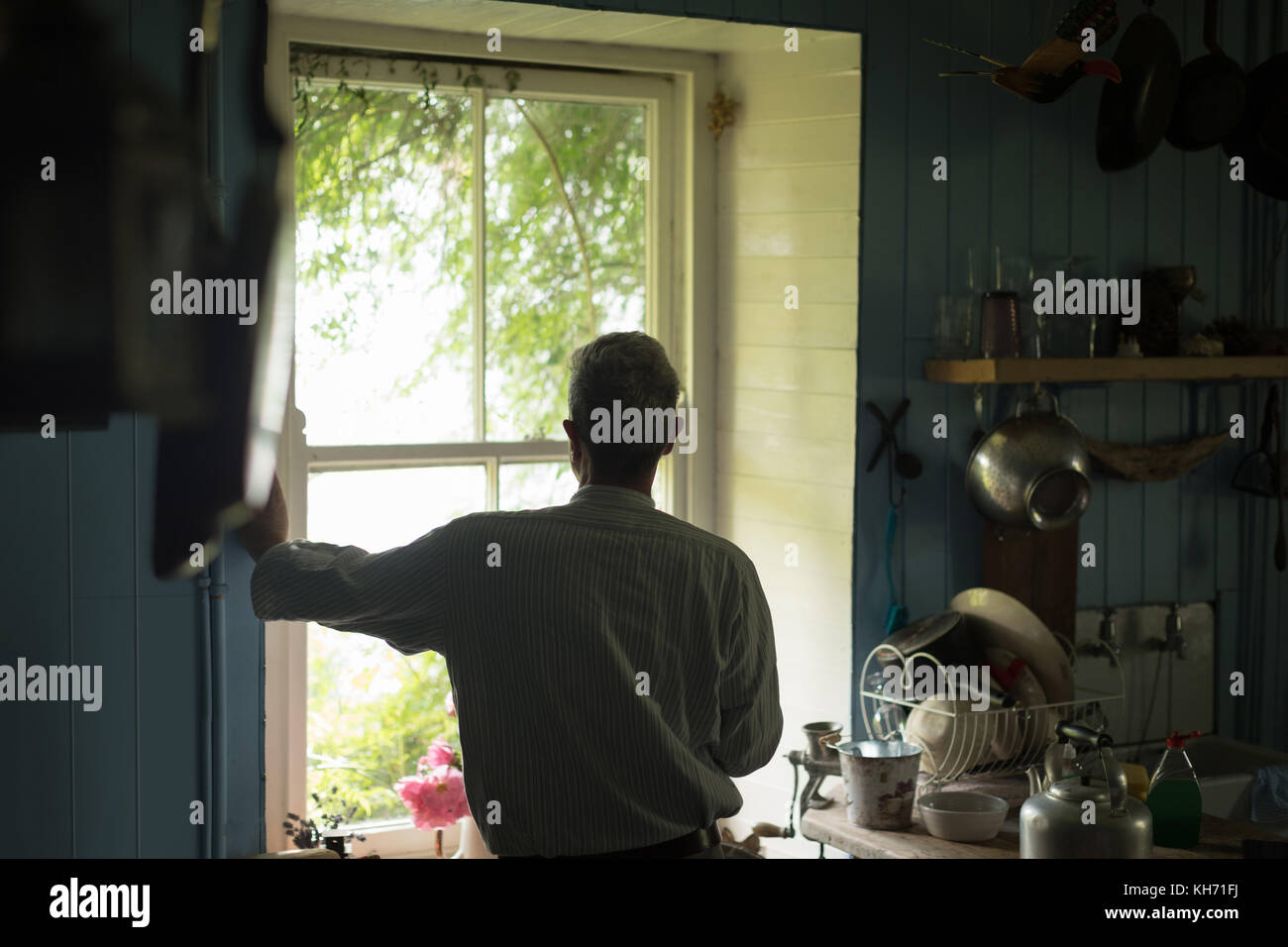 Thoughtful senior man looking through window in kitchen at home Stock ...