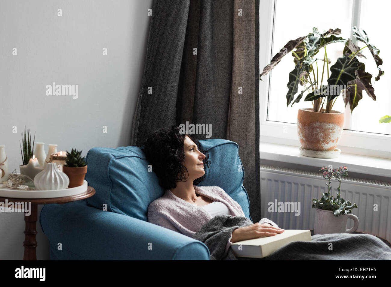 Beautiful woman relaxing on sofa and reading book at home Stock Photo ...