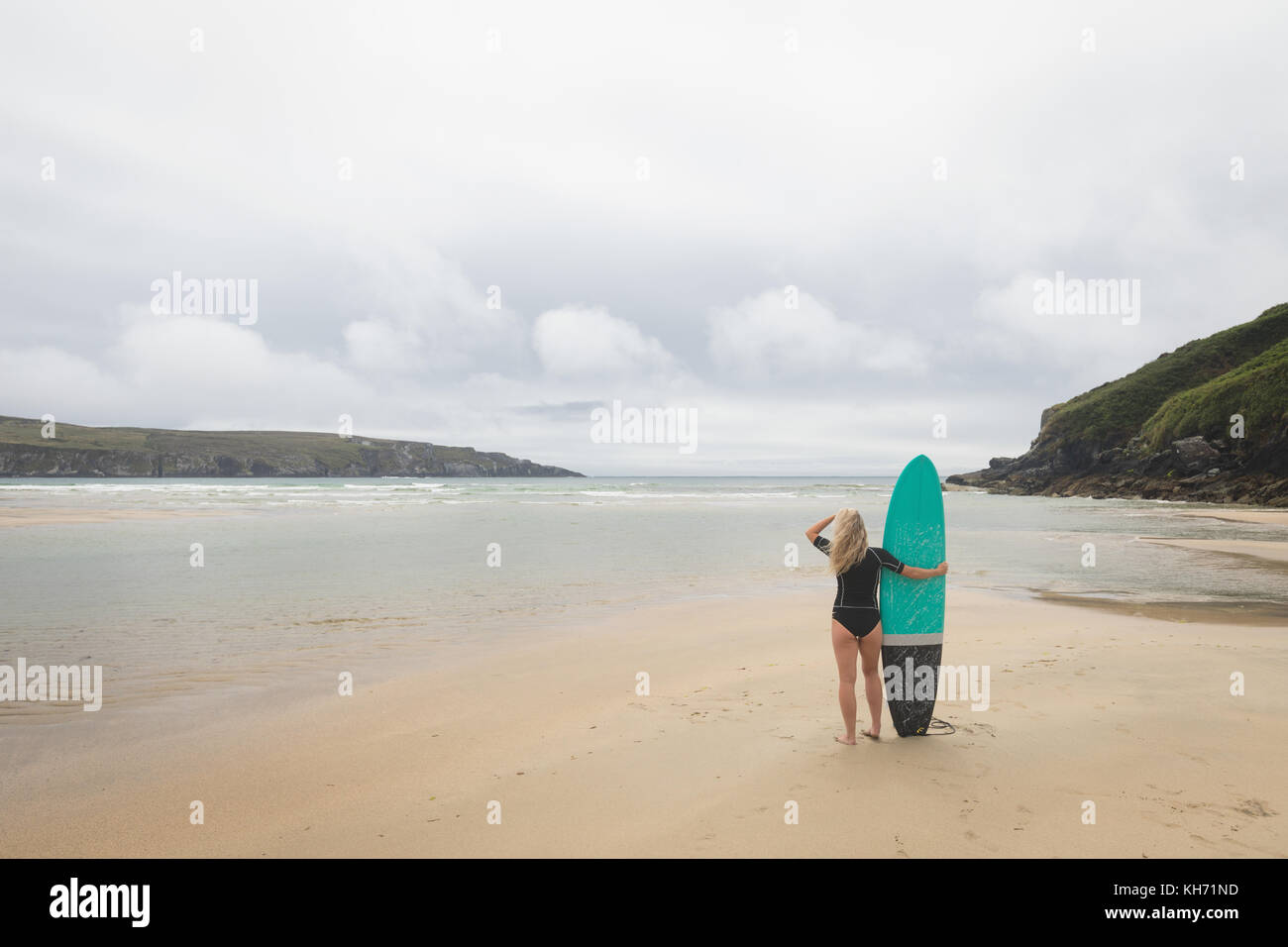 Rear view of female surfer standing with surfboard on beach Stock Photo ...