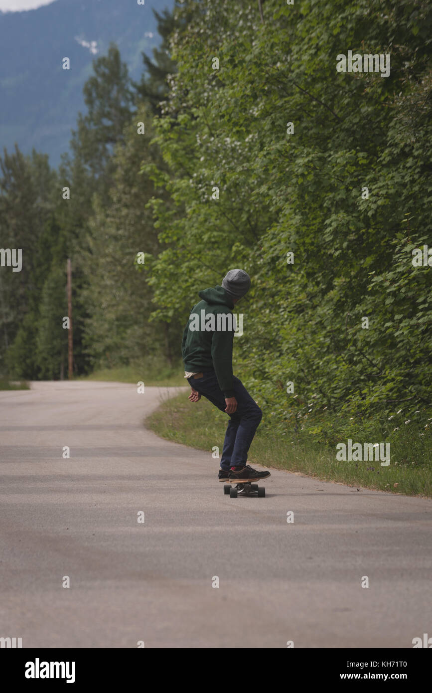 Rear view of skateboarder skating on road Stock Photo - Alamy