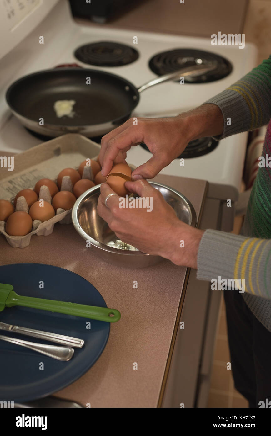 Man cracking egg into bowl in kitchen Stock Photo - Alamy