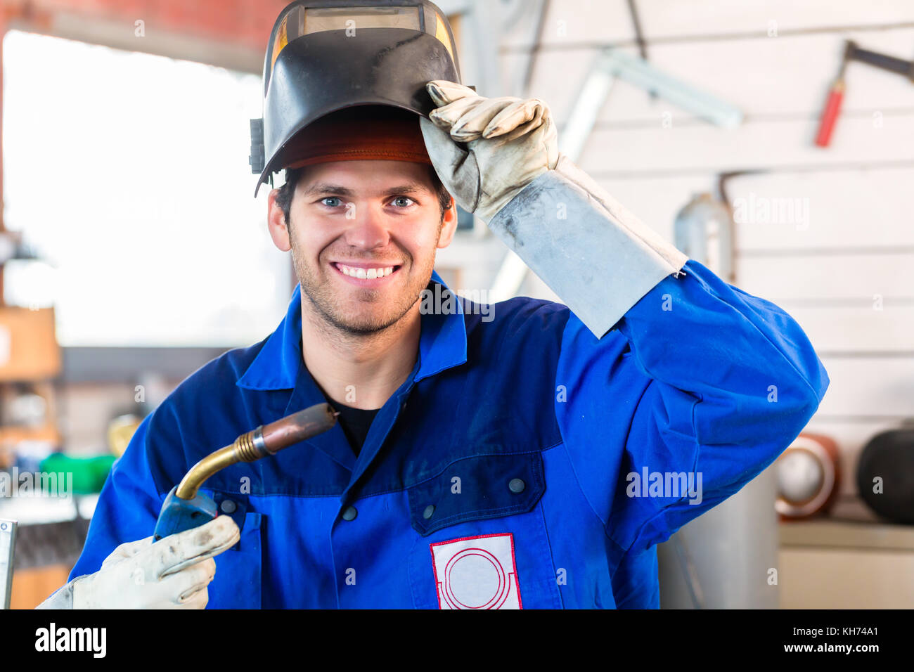 Welder with welding device in metal workshop looking into camera Stock ...