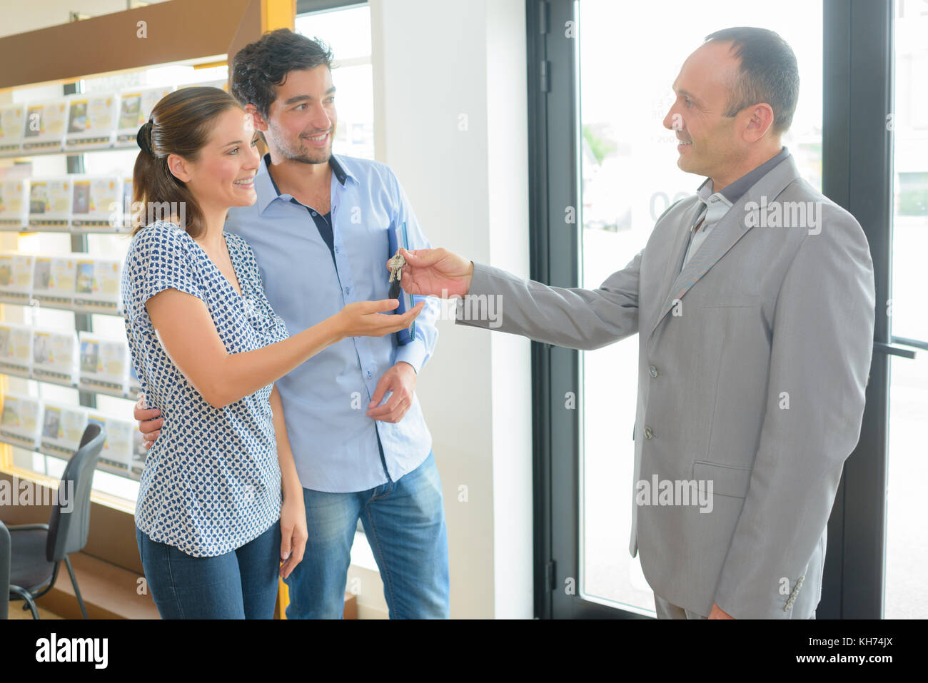 Estate agent passing keys to young couple Stock Photo - Alamy