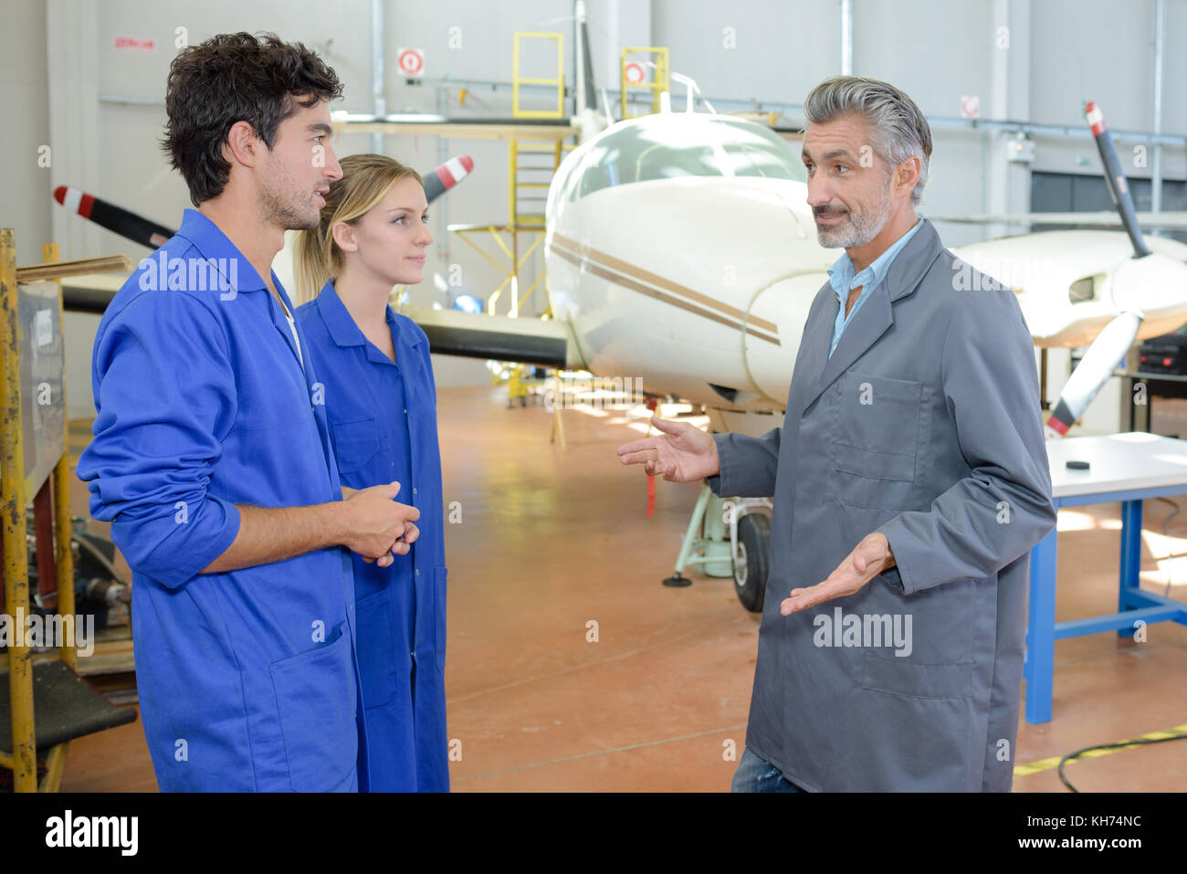 man answering students questions in aircraft hangar Stock Photo - Alamy