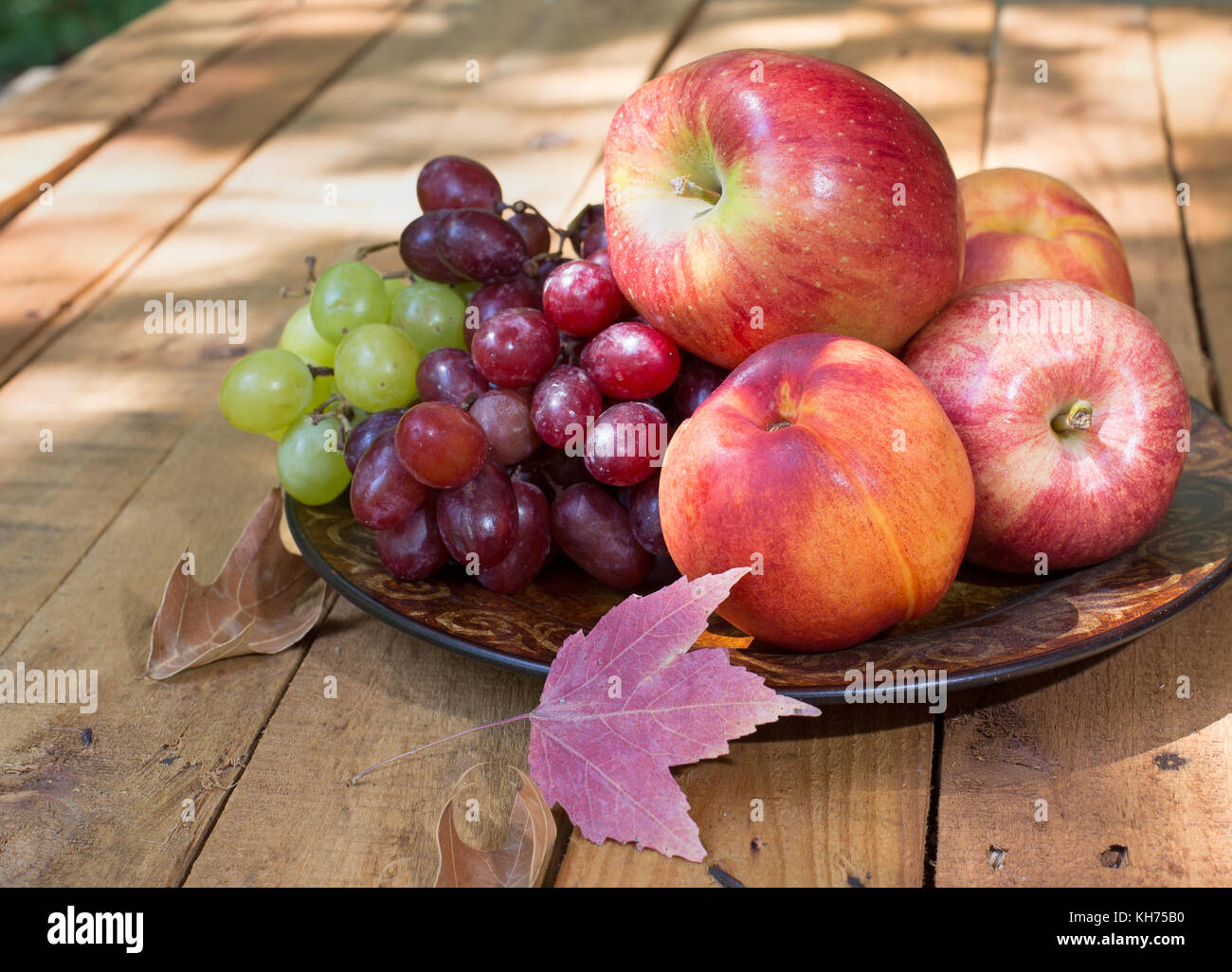 Plate of apples, peaches and grapes on a wooden surface Stock Photo - Alamy