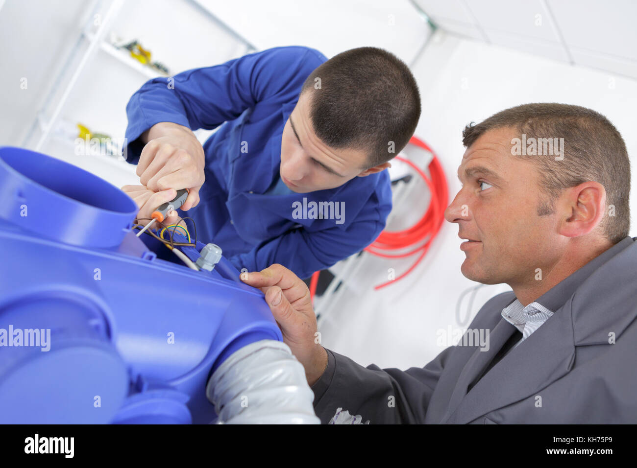 Man using screwdriver under supervision Stock Photo - Alamy