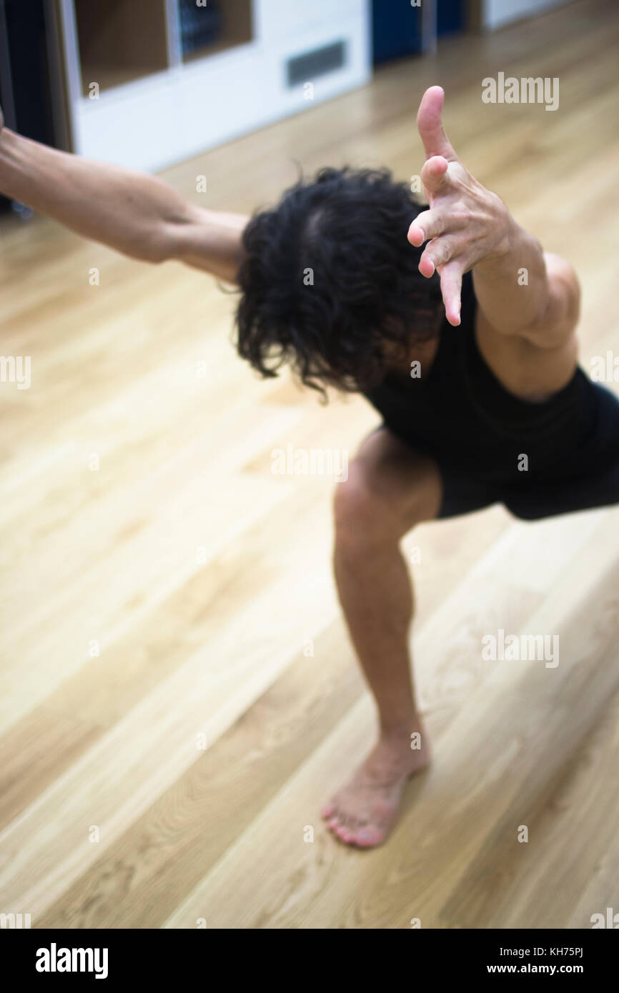 Man yoga teacher practising in gym fitness studio doing advanced asana ...