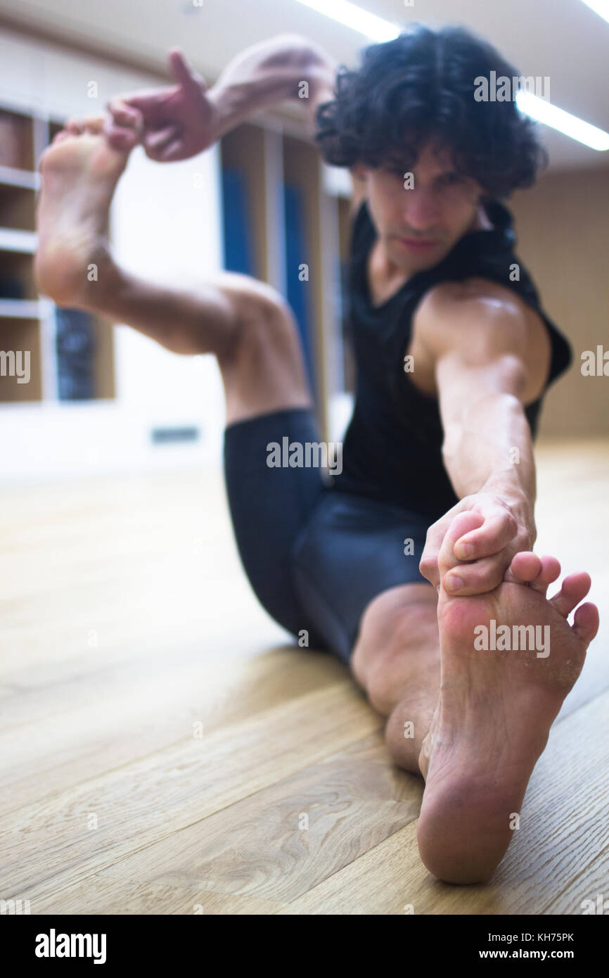 Man yoga teacher practising in gym fitness studio doing advanced asana ...
