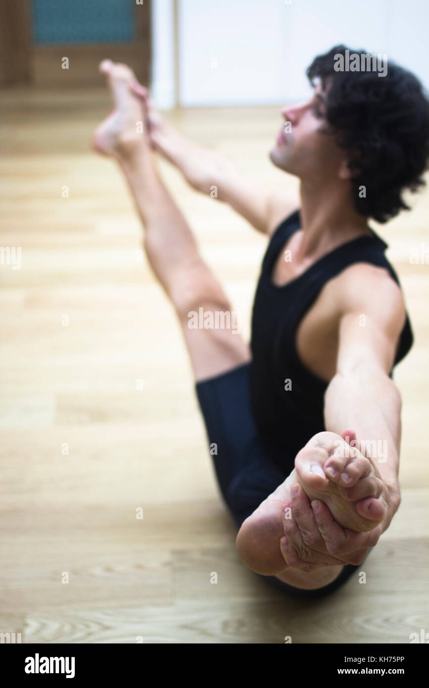 Man yoga teacher practising in gym fitness studio doing advanced asana ...