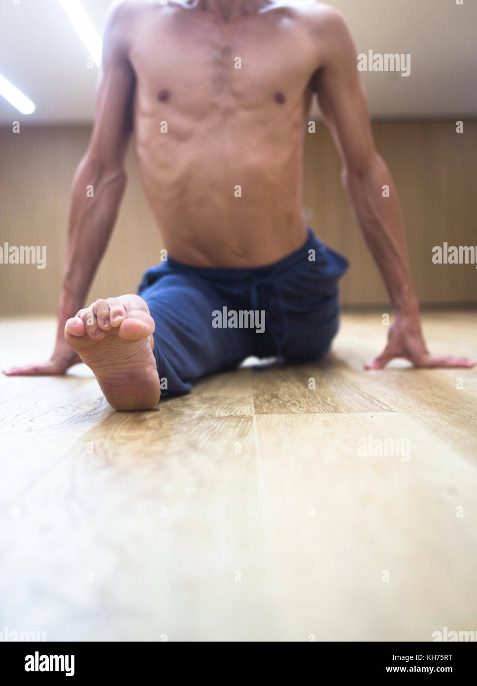 Man yoga teacher practising in gym fitness studio doing advanced asana ...