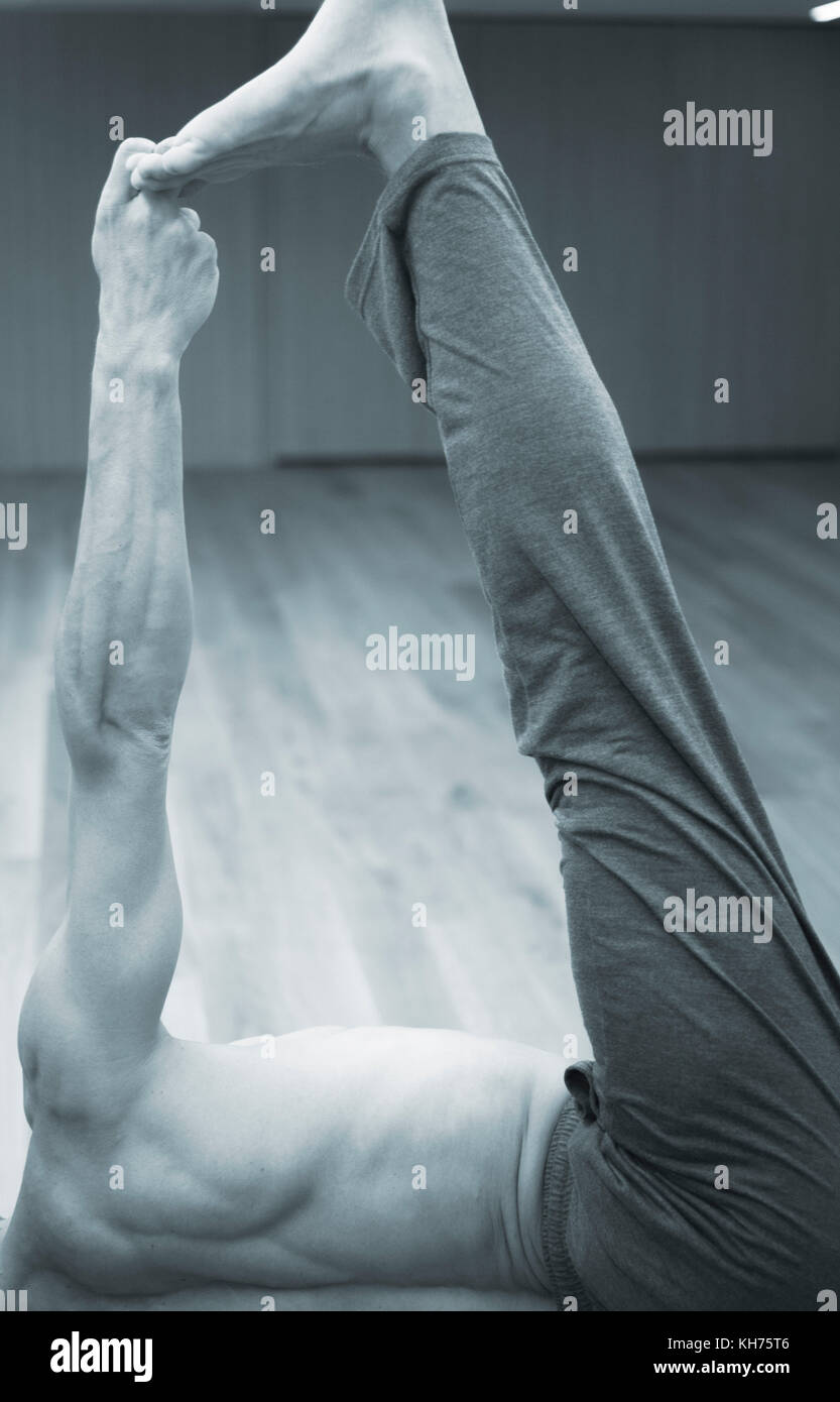 Man yoga teacher practising in gym fitness studio doing advanced asana ...