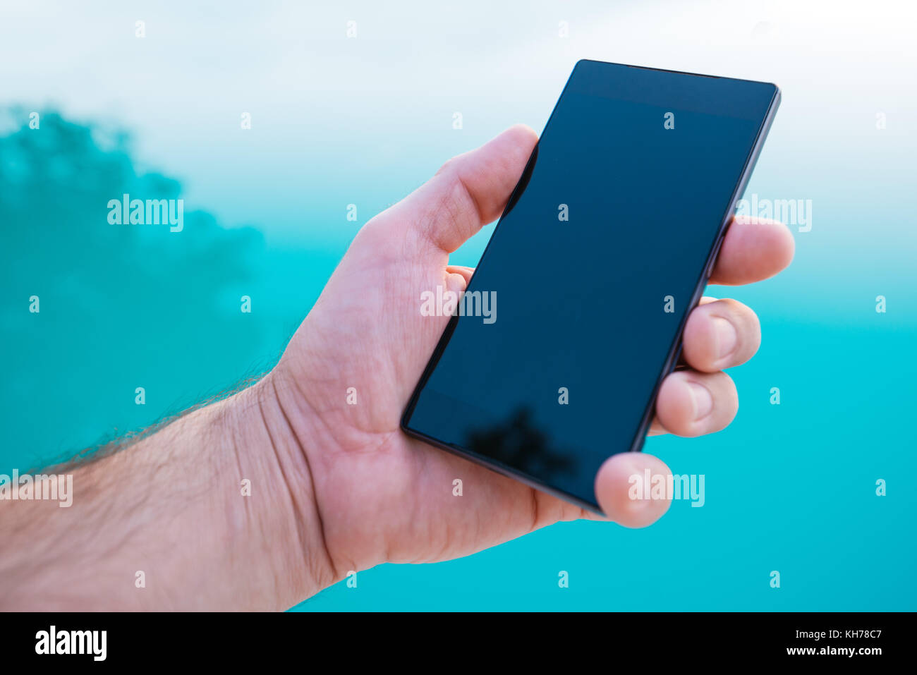 Using mobile phone by the swimming pool, male hand holding smartphone ...