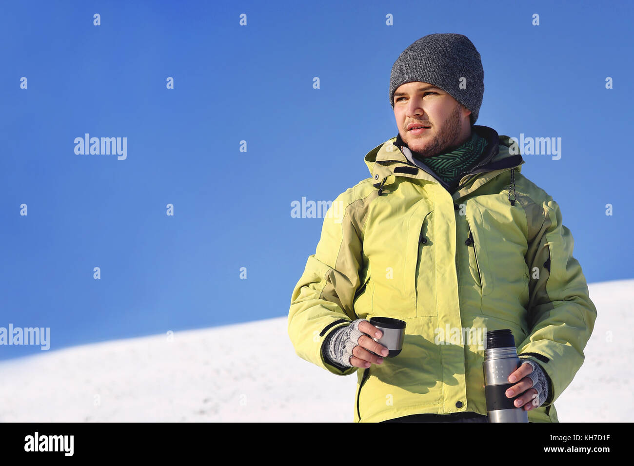 Man drinking hot coffee in thermos mug and looking into the mountains ...