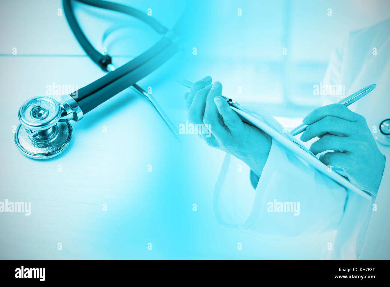 Mid section of a female doctor writing reports against stethoscope on ...