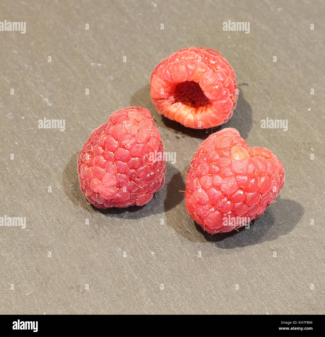 three ripe raspberries over background of black slate Stock Photo - Alamy