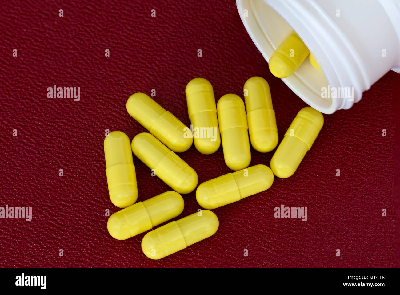 Yellow pill capsules with white pill container on red background Stock ...