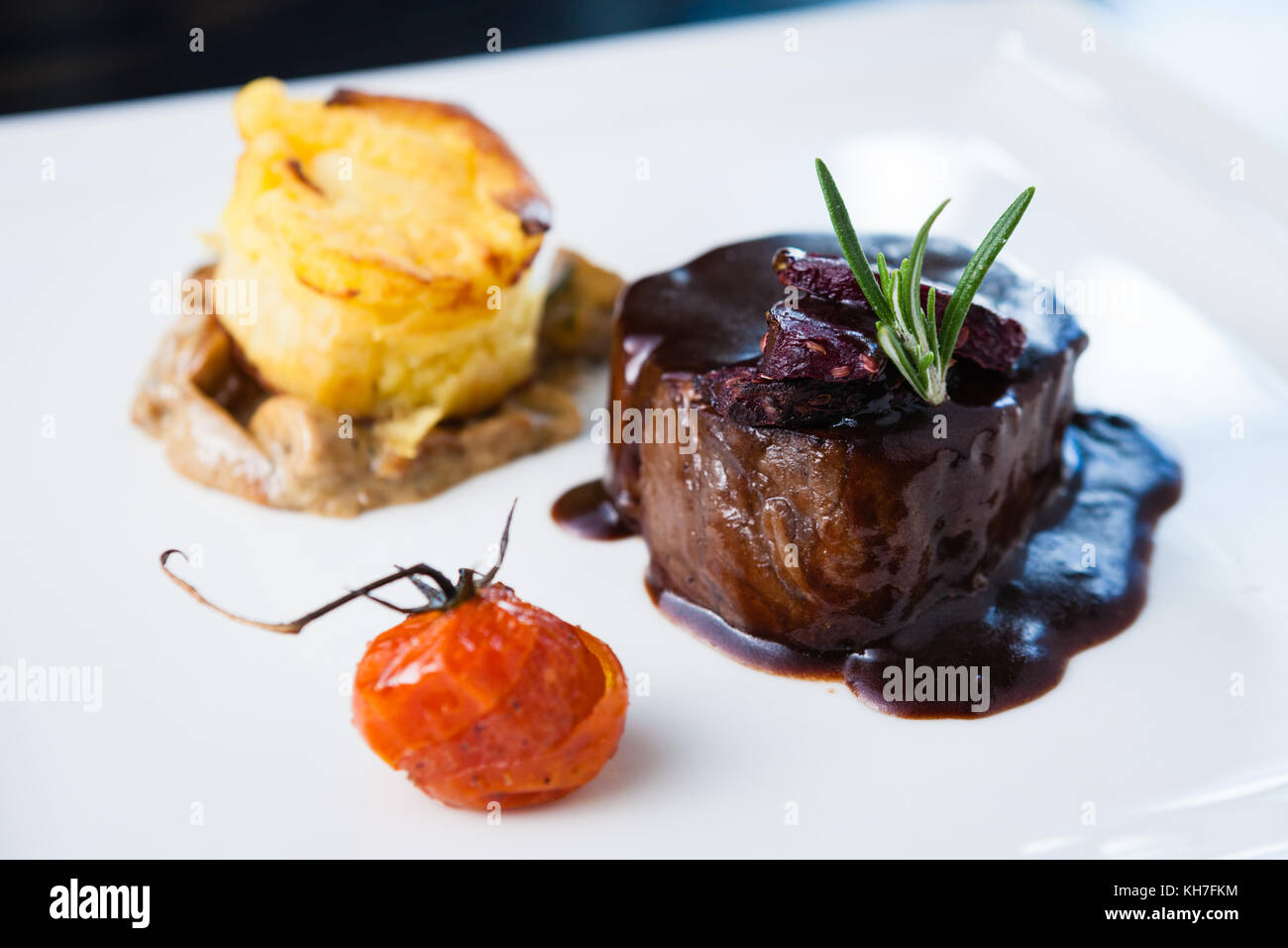 Roasted beef tenderloin with herb-potato muffin, mushroom ragout, baked tomatoes and rosemary ...