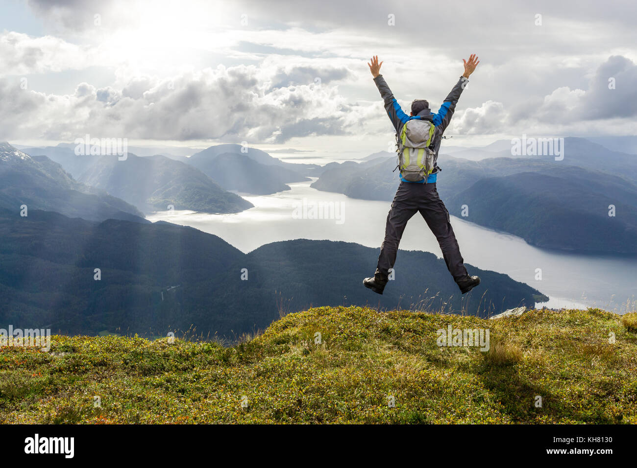 Man reaching summit and leaping for joy. Stunning view to coastal ...