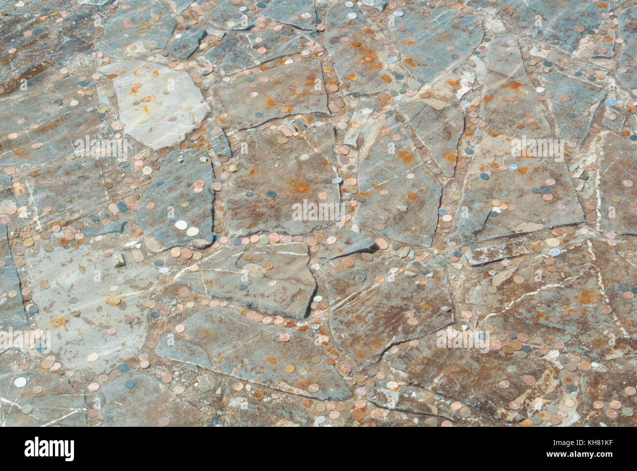 Background of an old fountain pond decorated with stones with coins ...