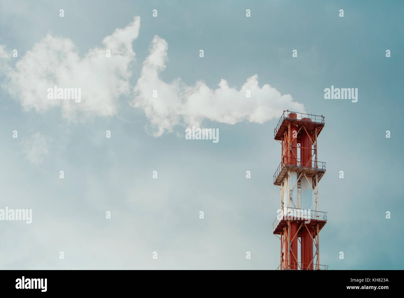 Close-up of red and white chimney with a cloud of white smoke against ...