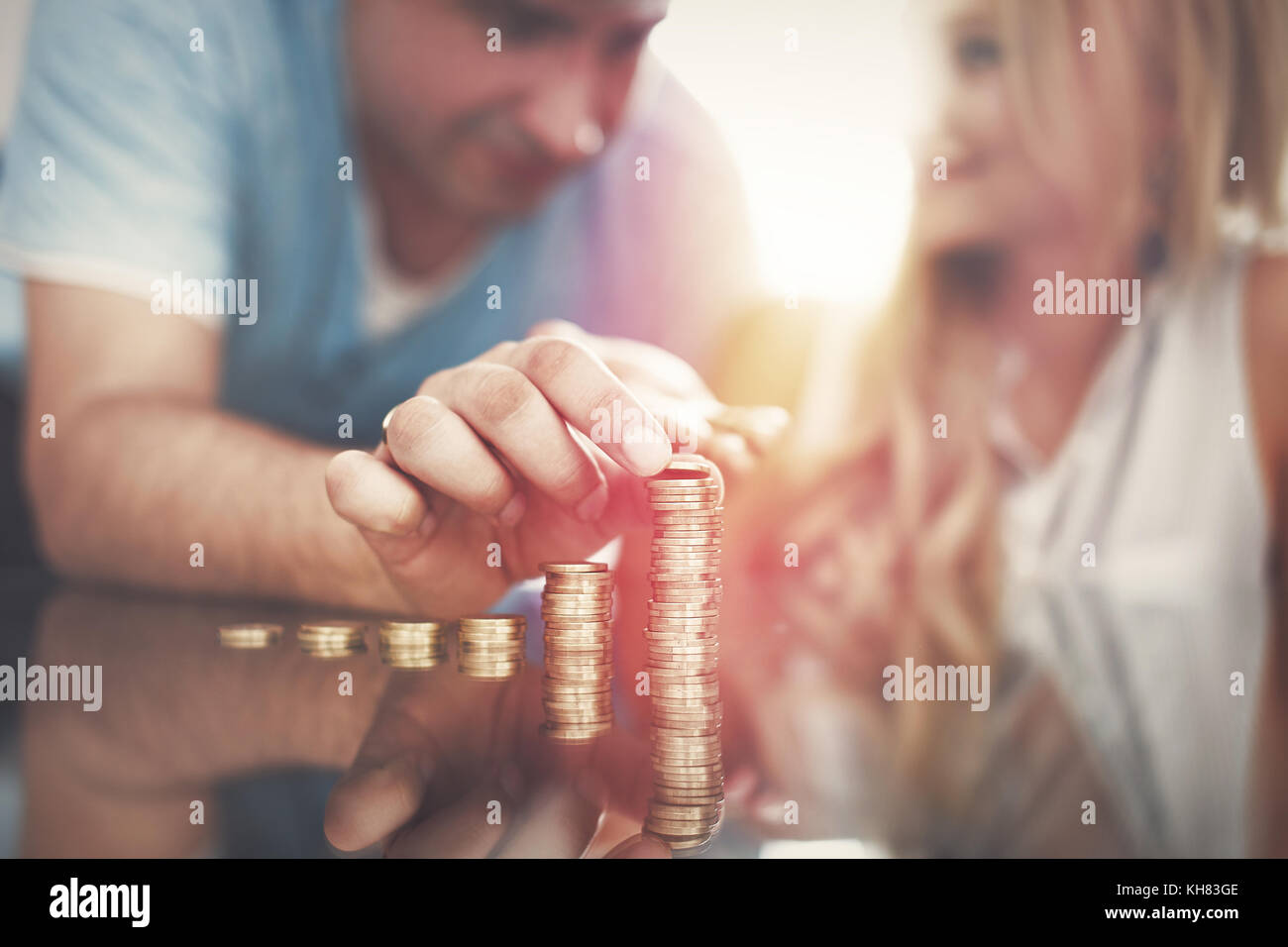 Young couple building money column on glass desk at home, cinematic ...