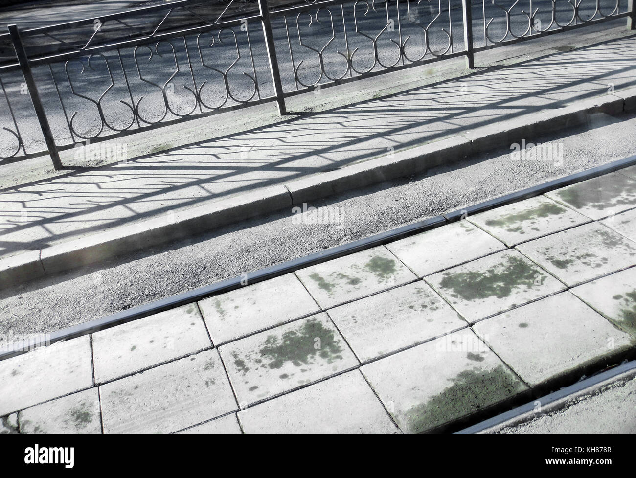 Diagonal shot. Tram tracks, sidewalk, fence and shades in sunny morning ...