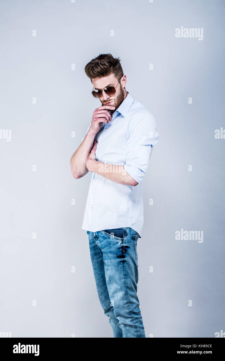 Young man standing in shirt, profile, hand on chin Stock Photo - Alamy