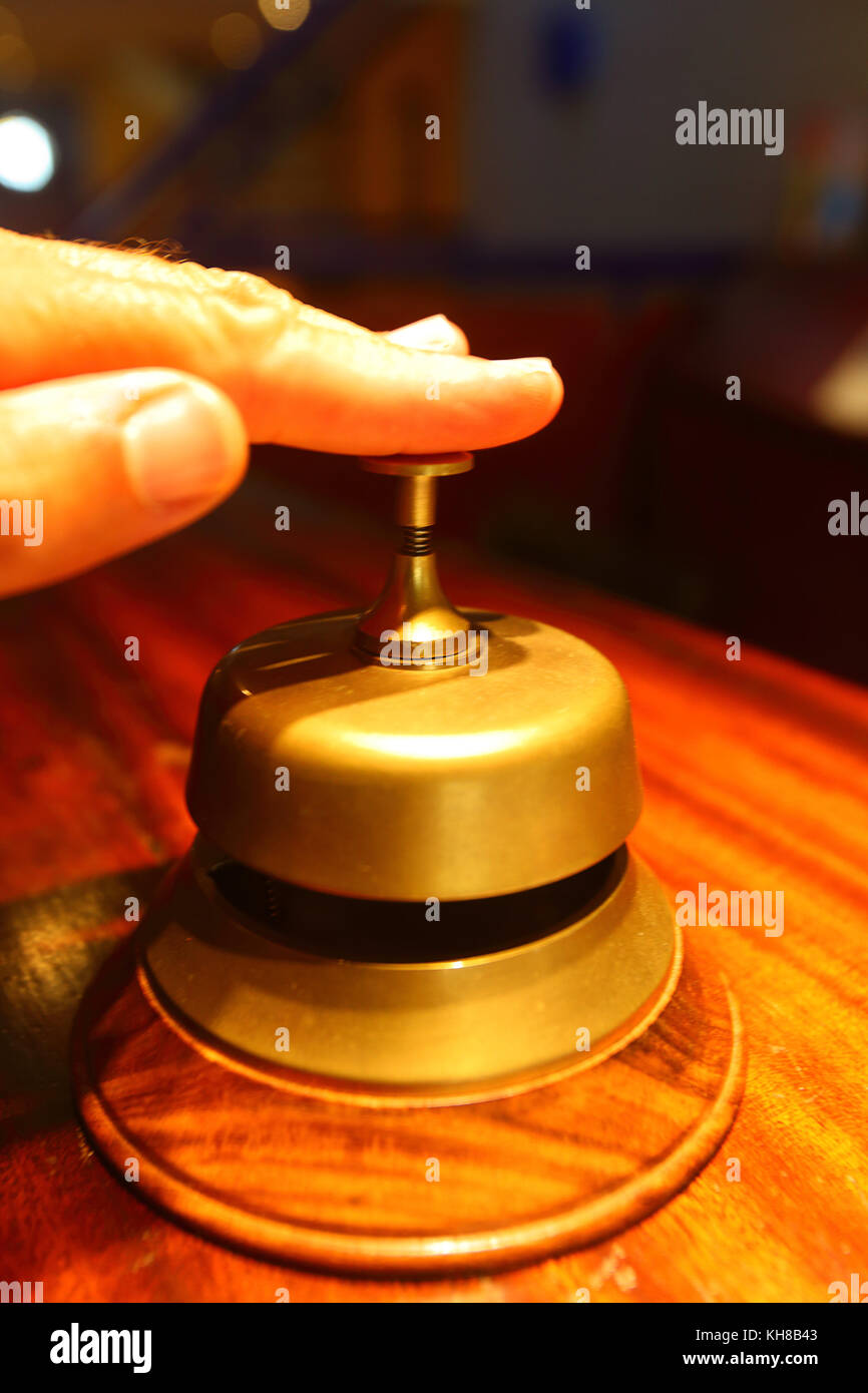 Hand pressing hotel bell Stock Photo - Alamy