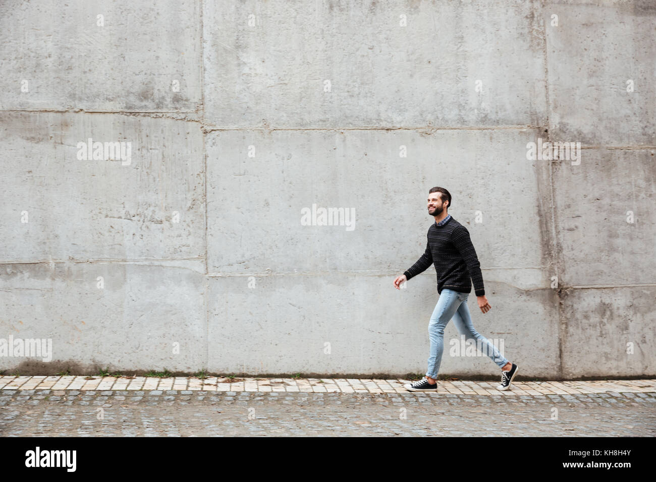 Full length portrait of a smiling casual man walking on a city street ...