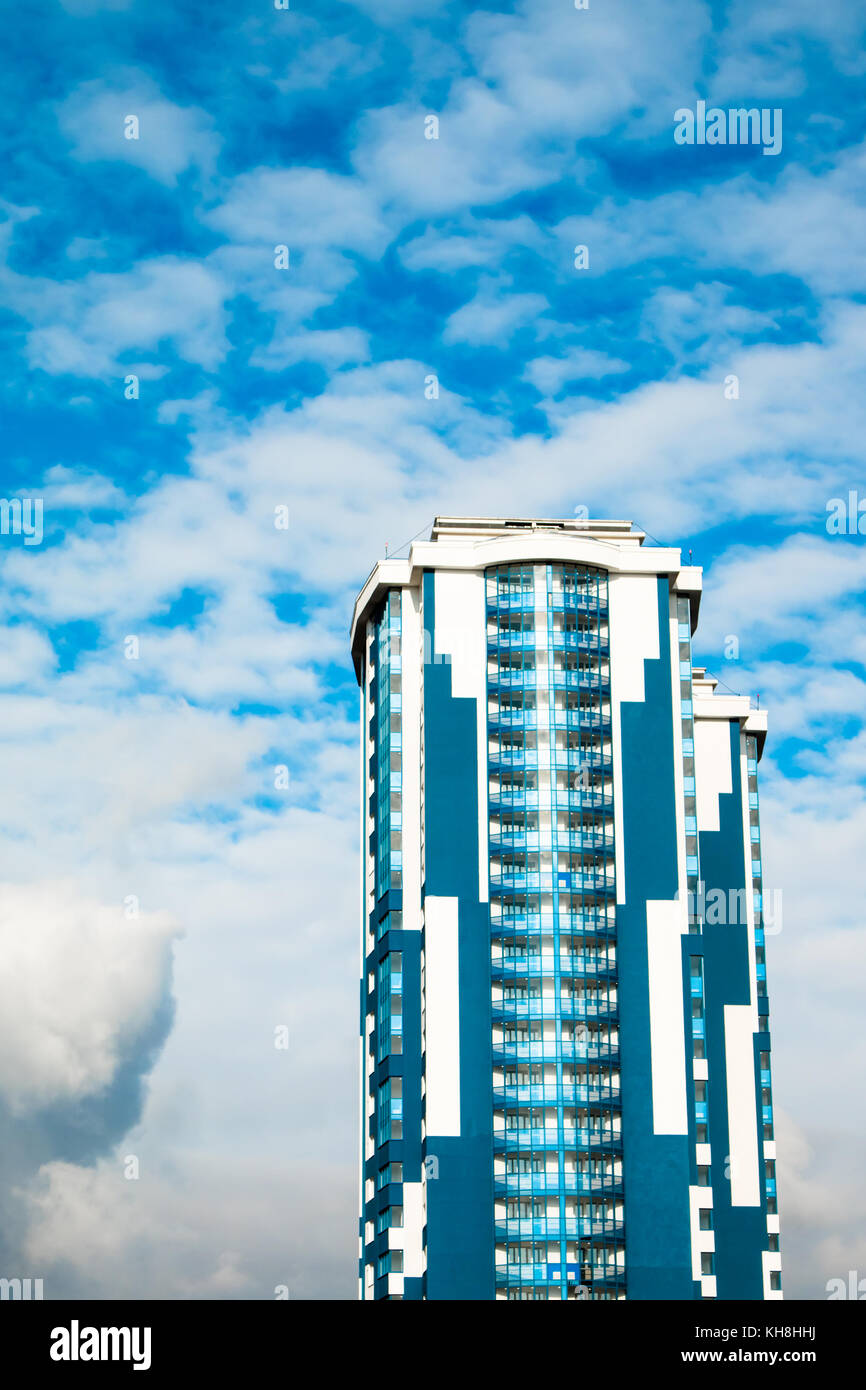 High-rise building with a glass facade against a bright blue sky with ...
