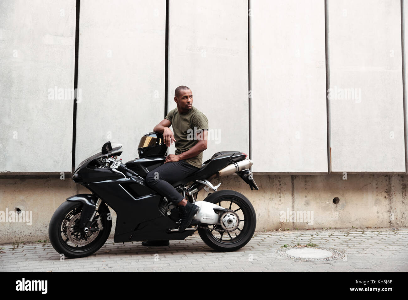 Portrait of a young afro american man sitting on a motorcycle outdoors ...