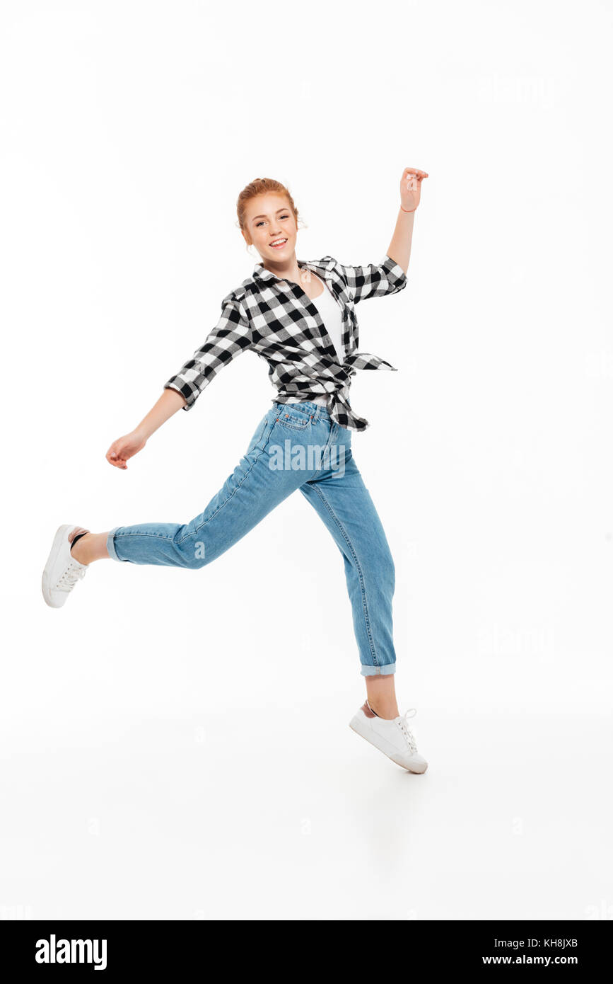 Full length image of happy ginger woman in shirt and jeans running and ...