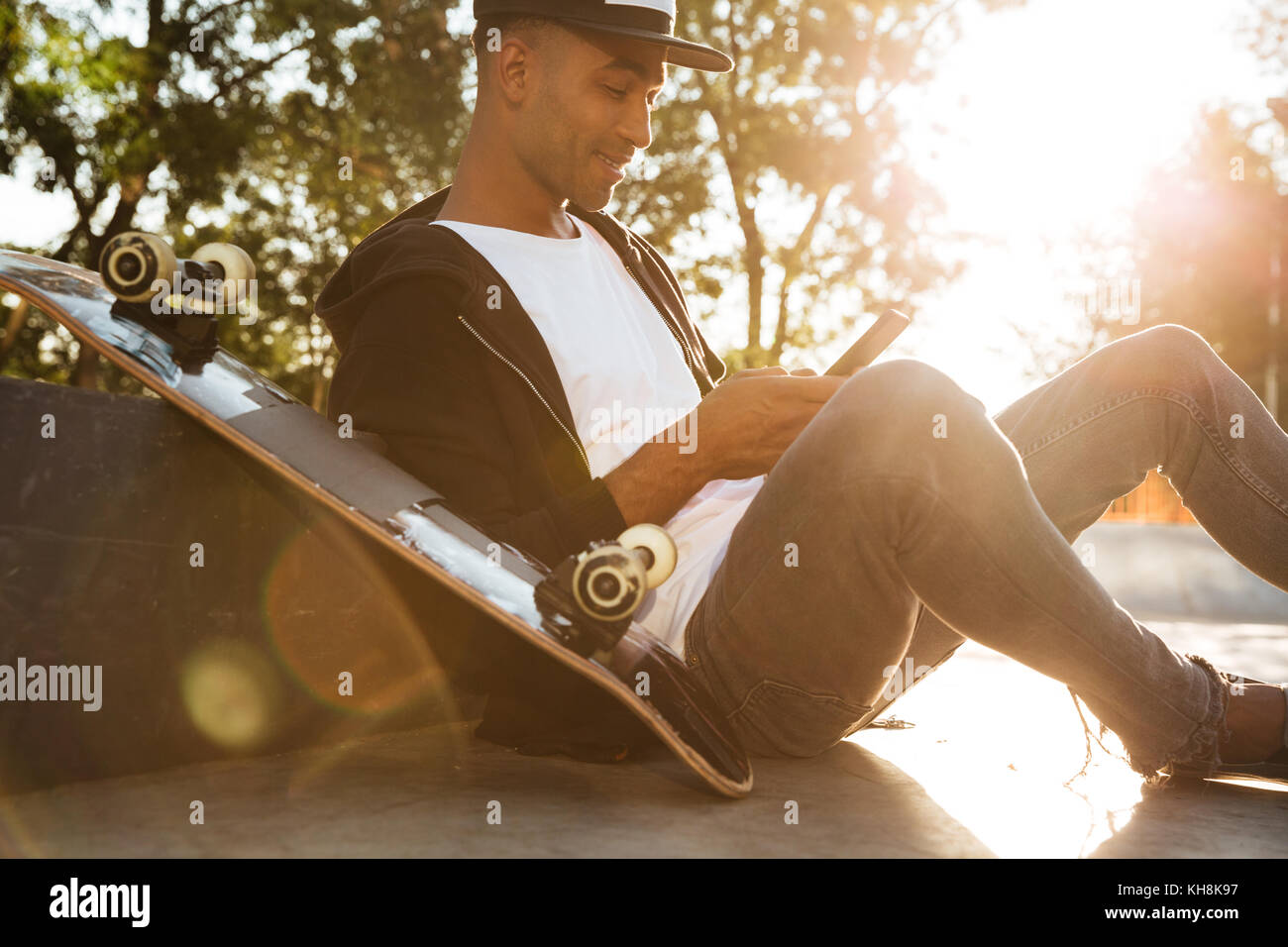 African young man surfing the web by using smartphone while sitting in ...