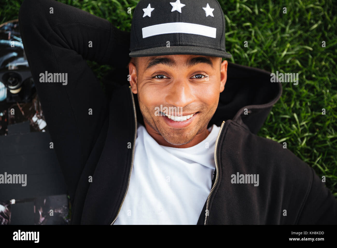 Top view of a smiling happy african male teenager lying on a grass with ...