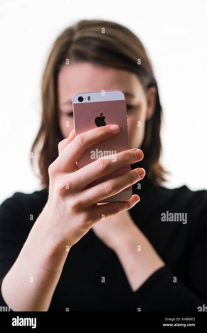 A young brown haired caucasian teenage girl on her Apple iPhone mobile ...